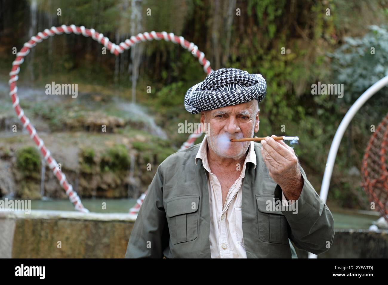 Kurdish man smoking a cigarette in a holder at a tourist viewpoint on ...