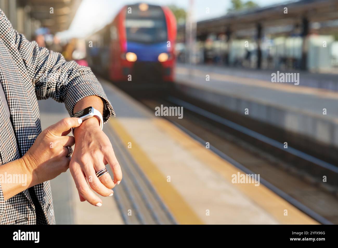 Female commuter checks the time on her smartwatch while standing on the ...