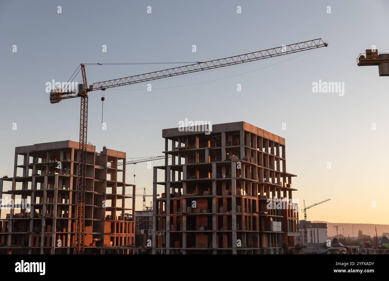 A construction crane silhouetted against the warm glow of an early ...