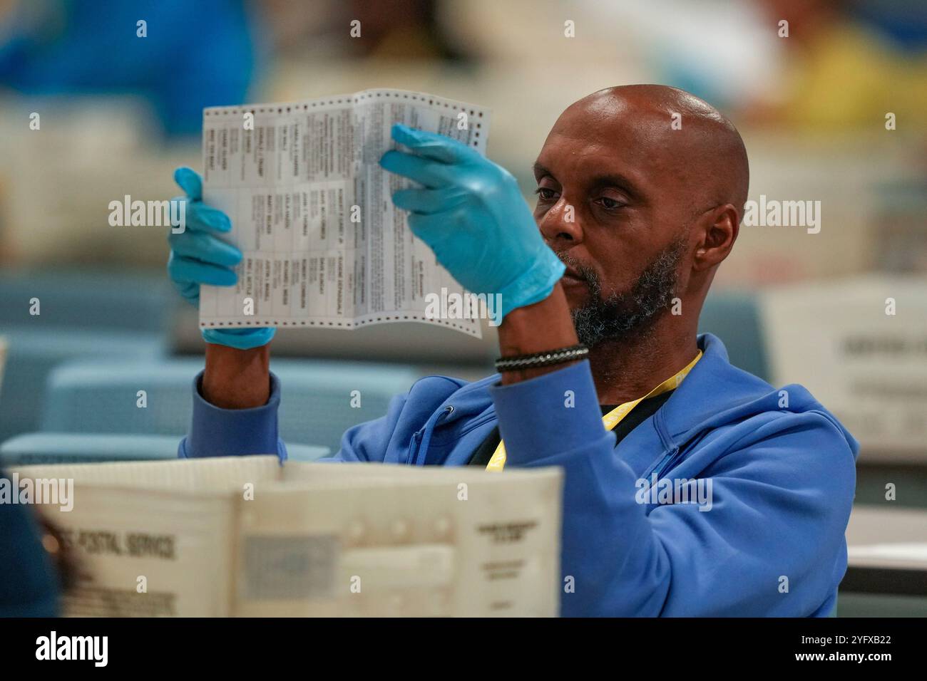 An election worker processes mail-in ballots for the 2024 General ...