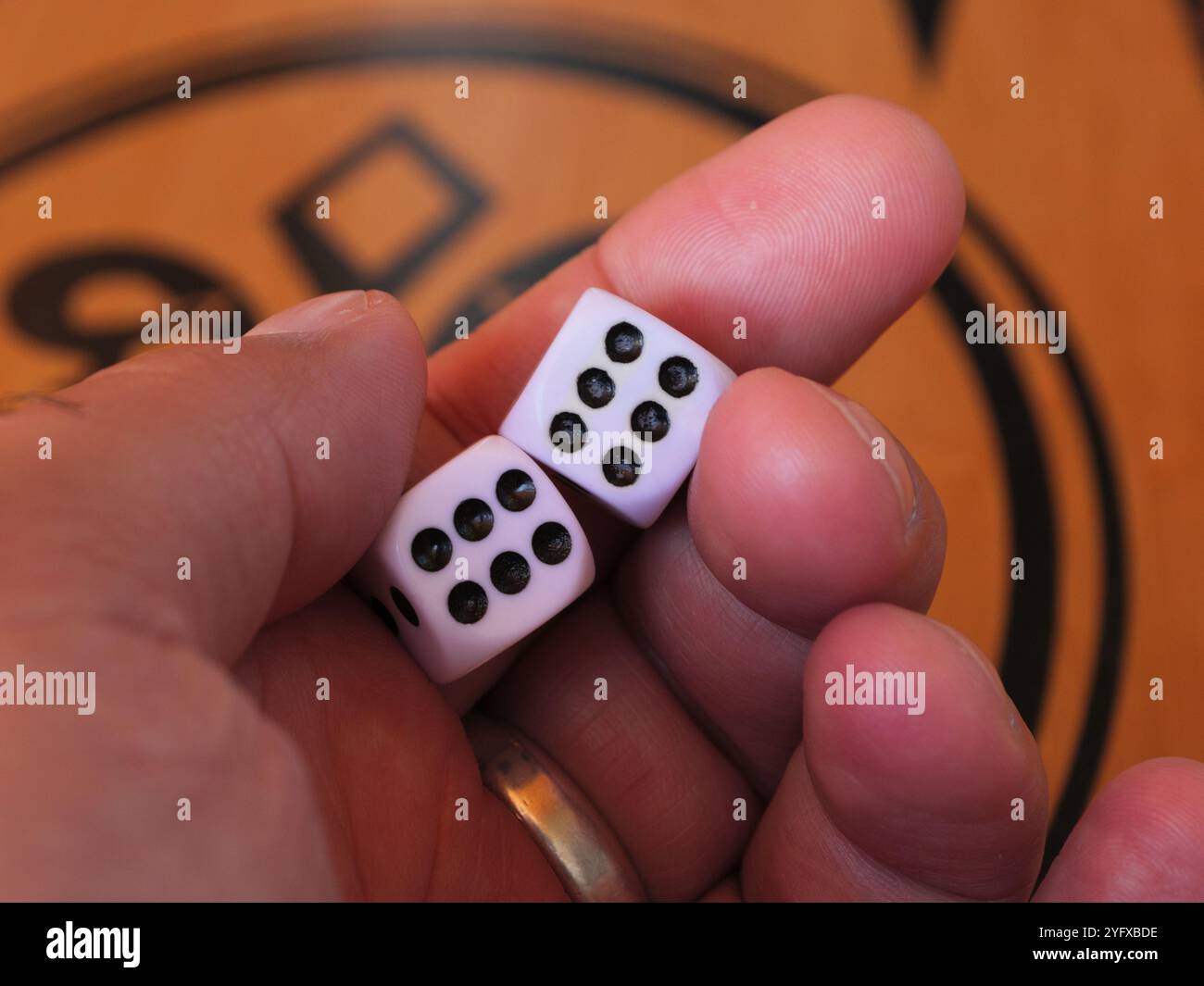 A hand shows two six-sided dice showing Double Six with black dots ...
