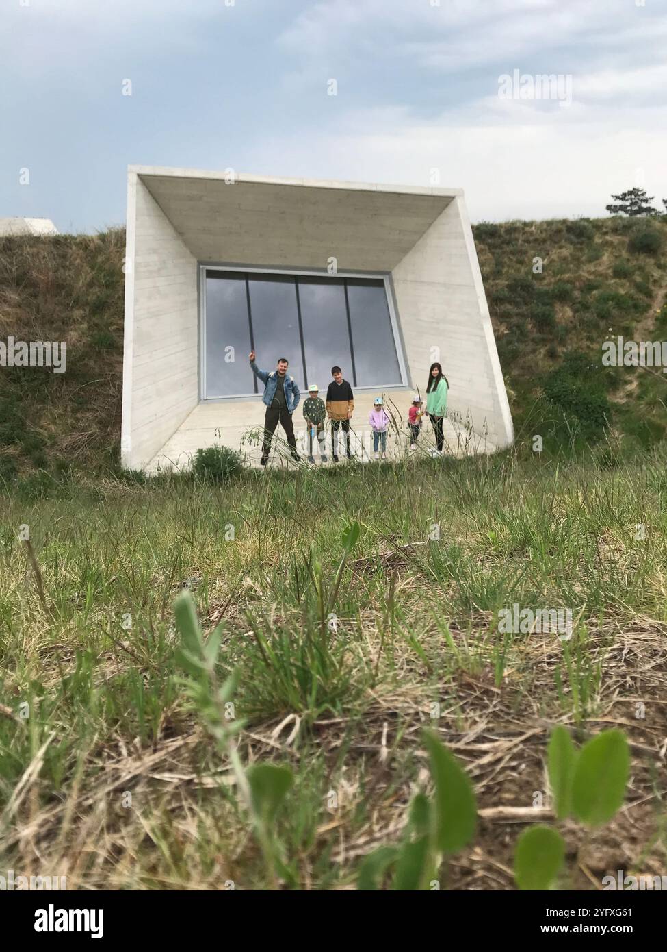 A family standing together outside a modern, geometric building with ...