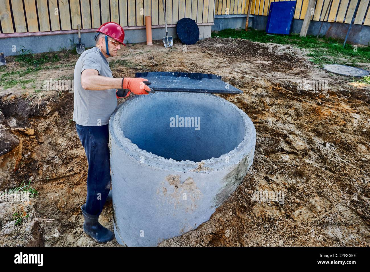 Builder installs support ring for manhole cover on concrete septic tank ...