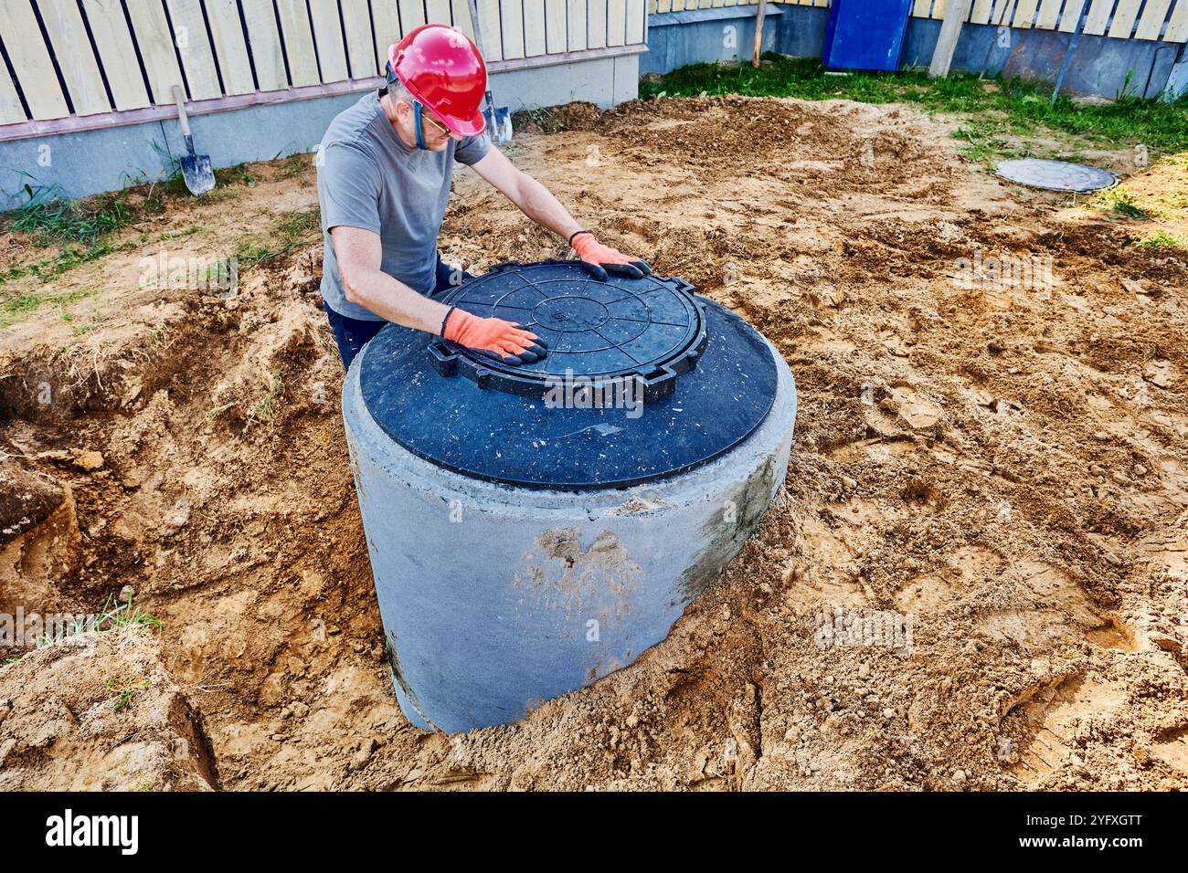Mature male builder installed manhole cover on concrete septic tank ...