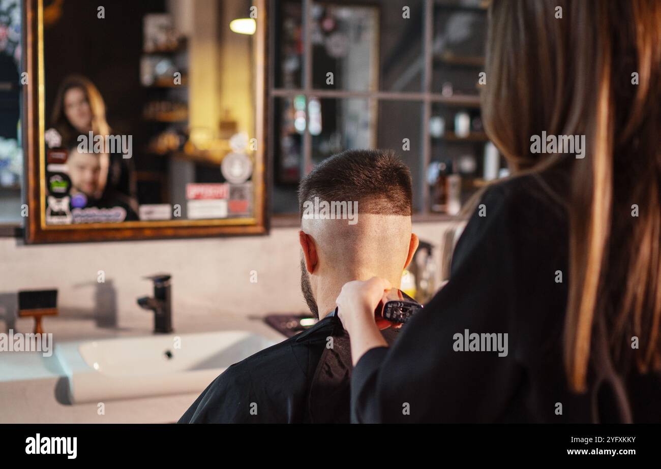 Young female barber making men's undercut haircut hairstyle using ...
