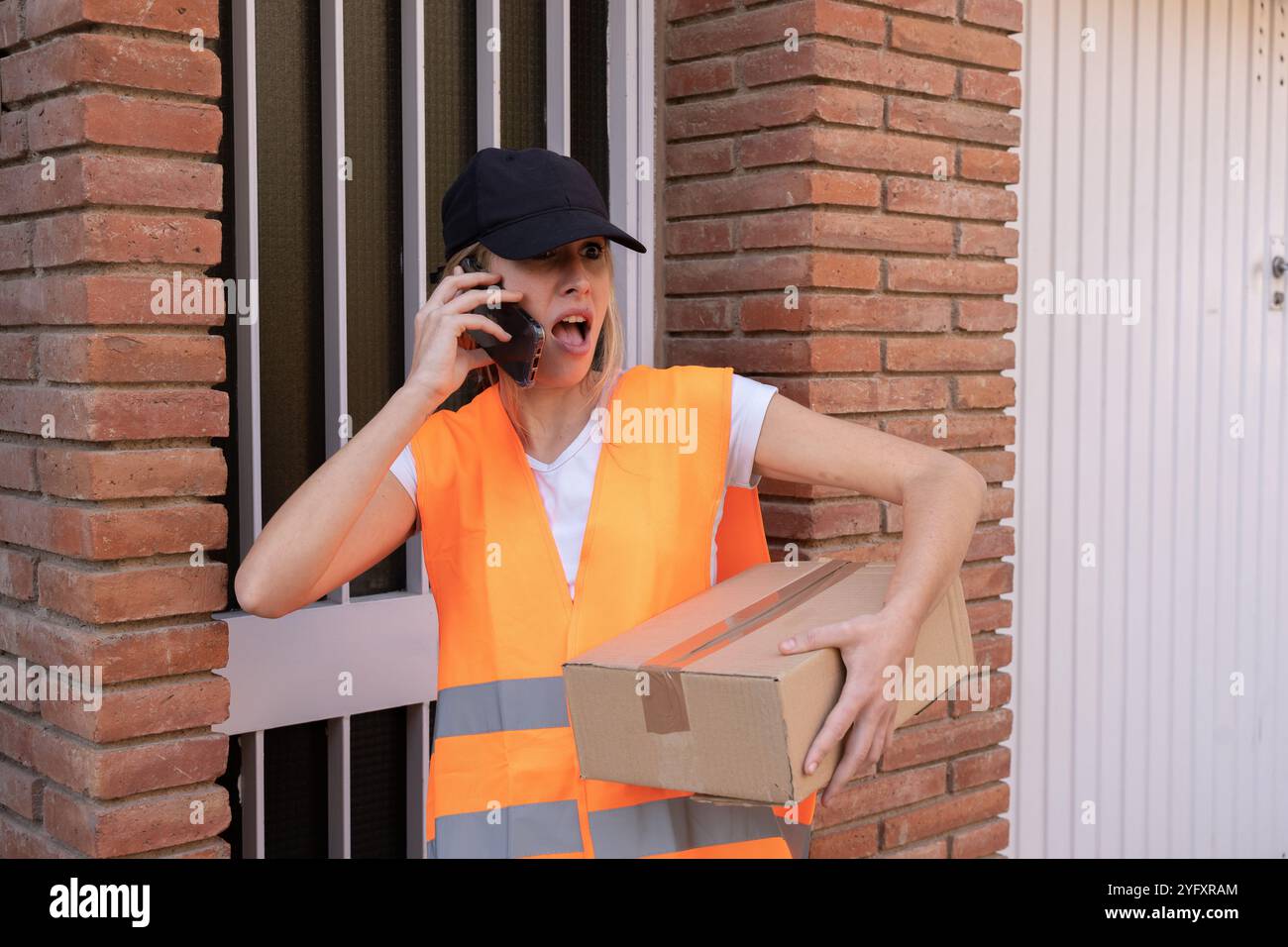 Woman working as a package delivery girl talking on the mobile phone ...