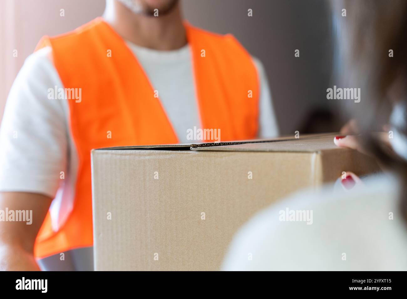 Delivery man giving a cardboard package to customer at home. Closeup of ...
