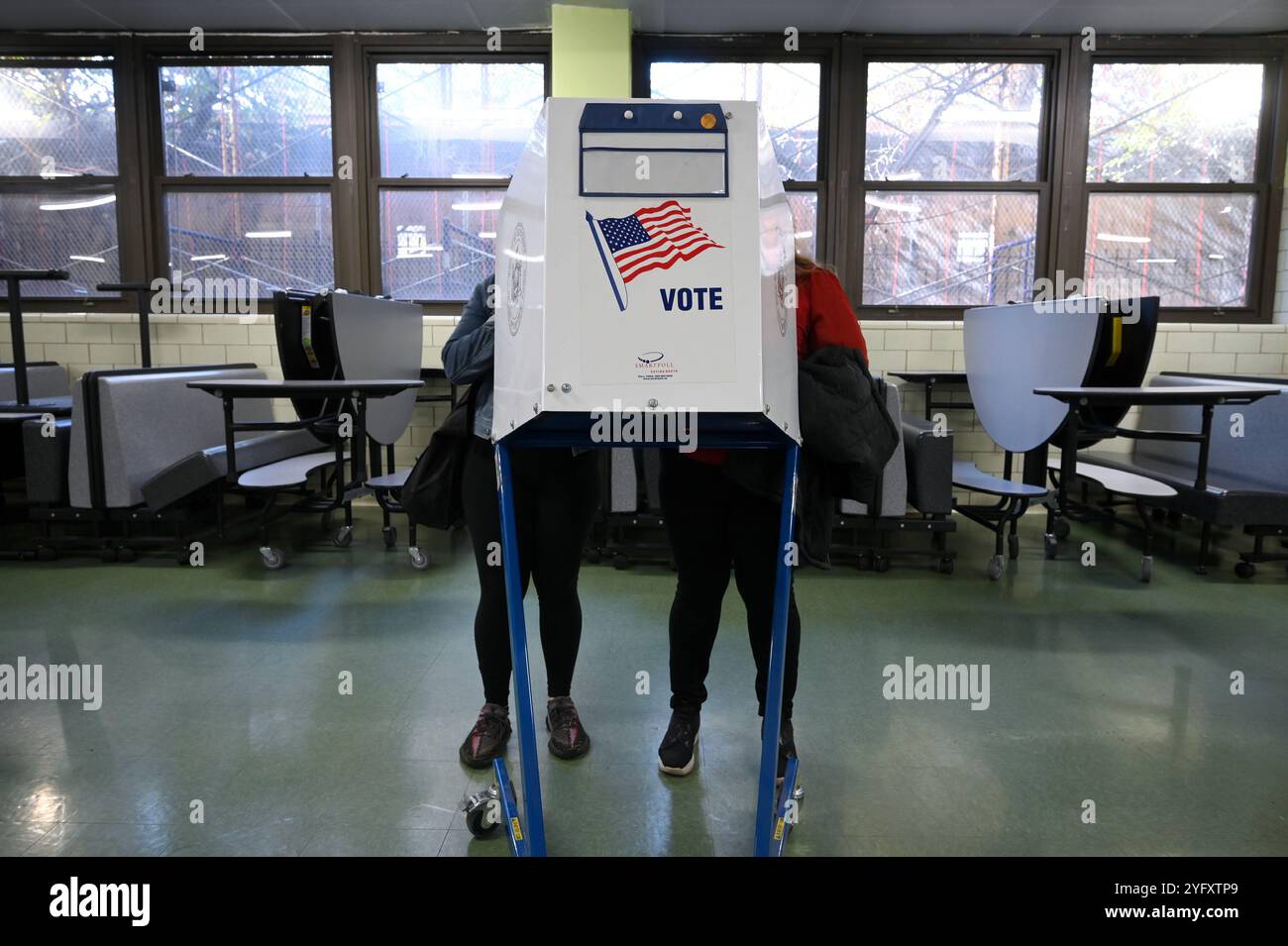 Two women stand a privacy booth as they vote together on National ...