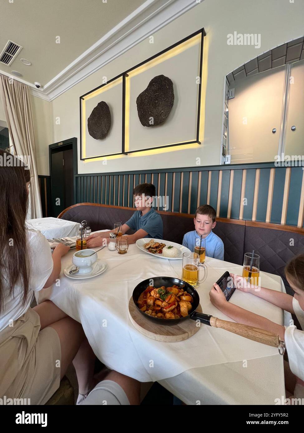 A family enjoys a meal together in a cozy restaurant, with children ...