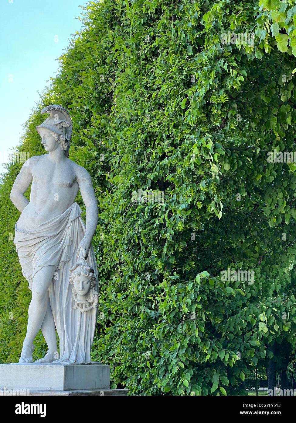 A classical marble statue of a Greek warrior stands amidst vibrant ...