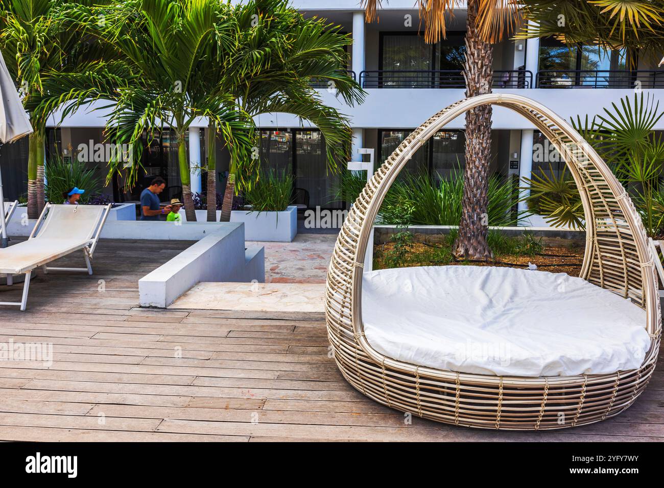 Outdoor lounge area with cozy rattan daybed surrounded by tropical palm ...