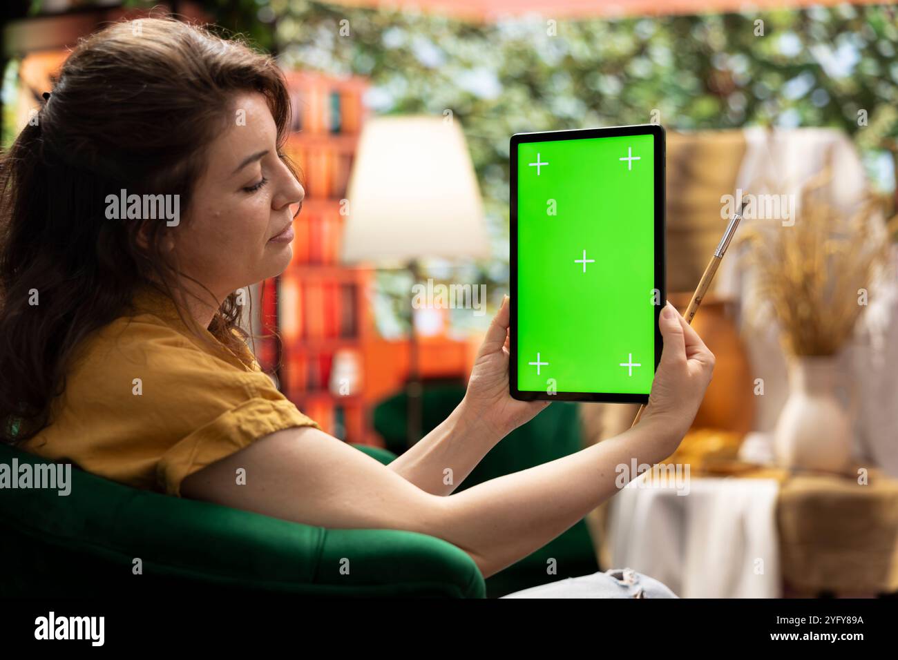 Female artist holding device with green screen in art and craft atelier ...