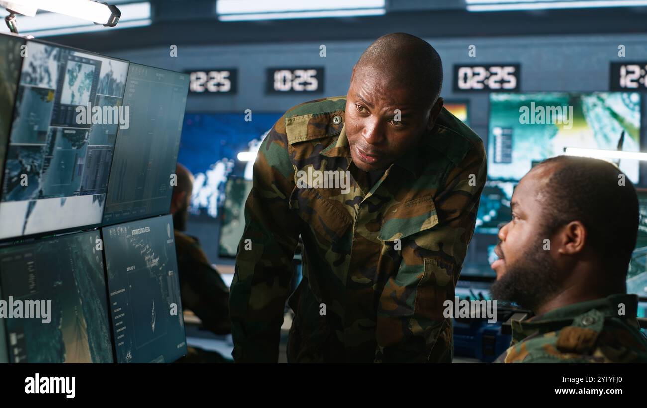 Team of soldiers looking at screens in command center housing ...