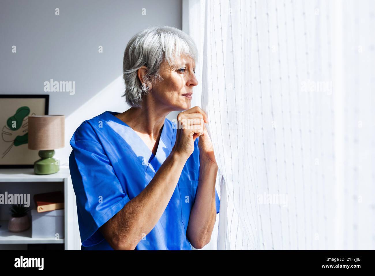 Middle aged doctor woman peeking looking through the curtain on window ...