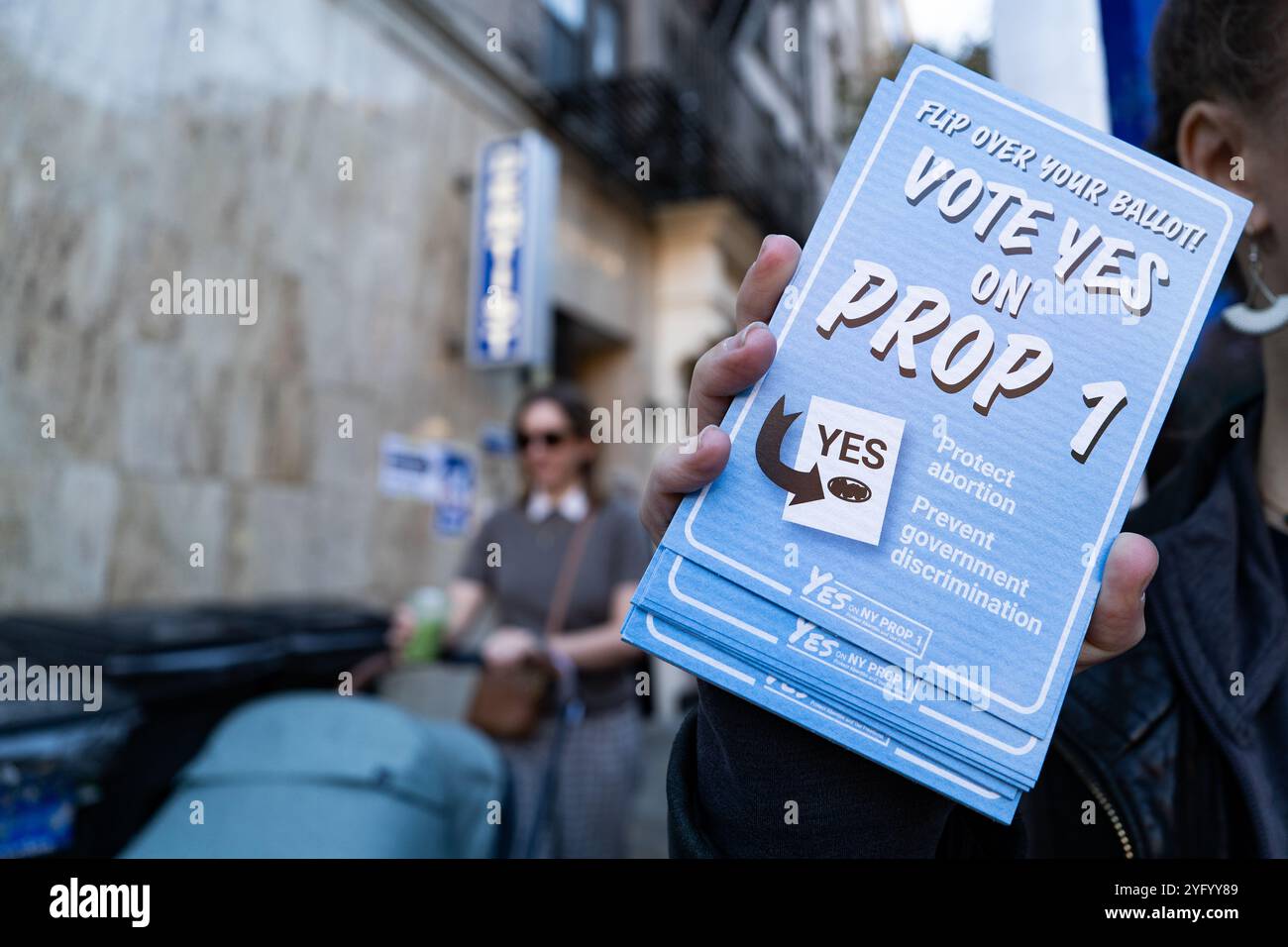 A woman holds up flyers outside a polling station asking people to flip ...