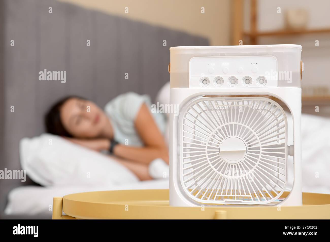 Portable table fan with humidifier and young sleeping woman in bedroom ...