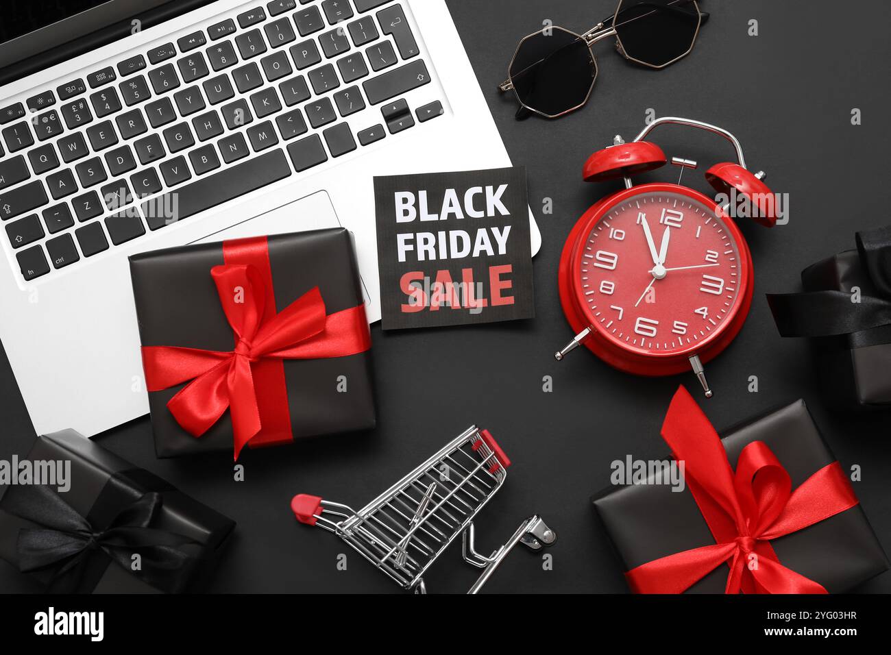Composition with modern laptop, gift boxes and small shopping cart on ...