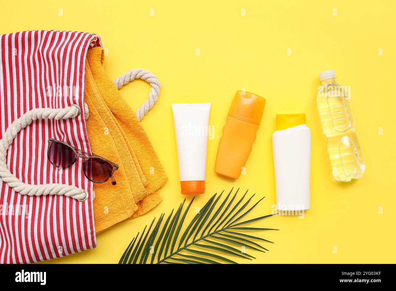 Composition with bottles of sunscreen cream, palm leaf, bag and ...