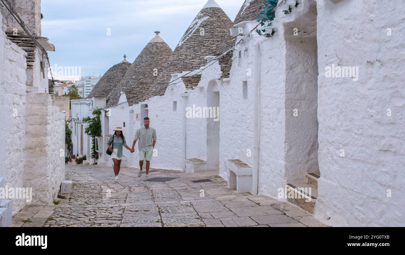 Alberobello A couple strolls hand in hand along the picturesque ...