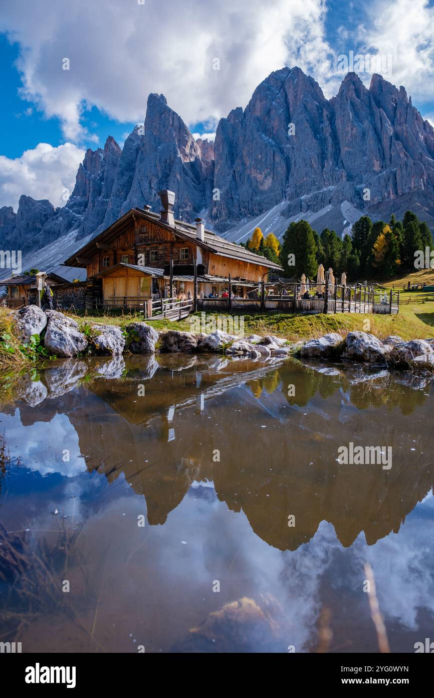 Amidst the towering Dolomites, a rustic cabin sits peacefully beside a ...