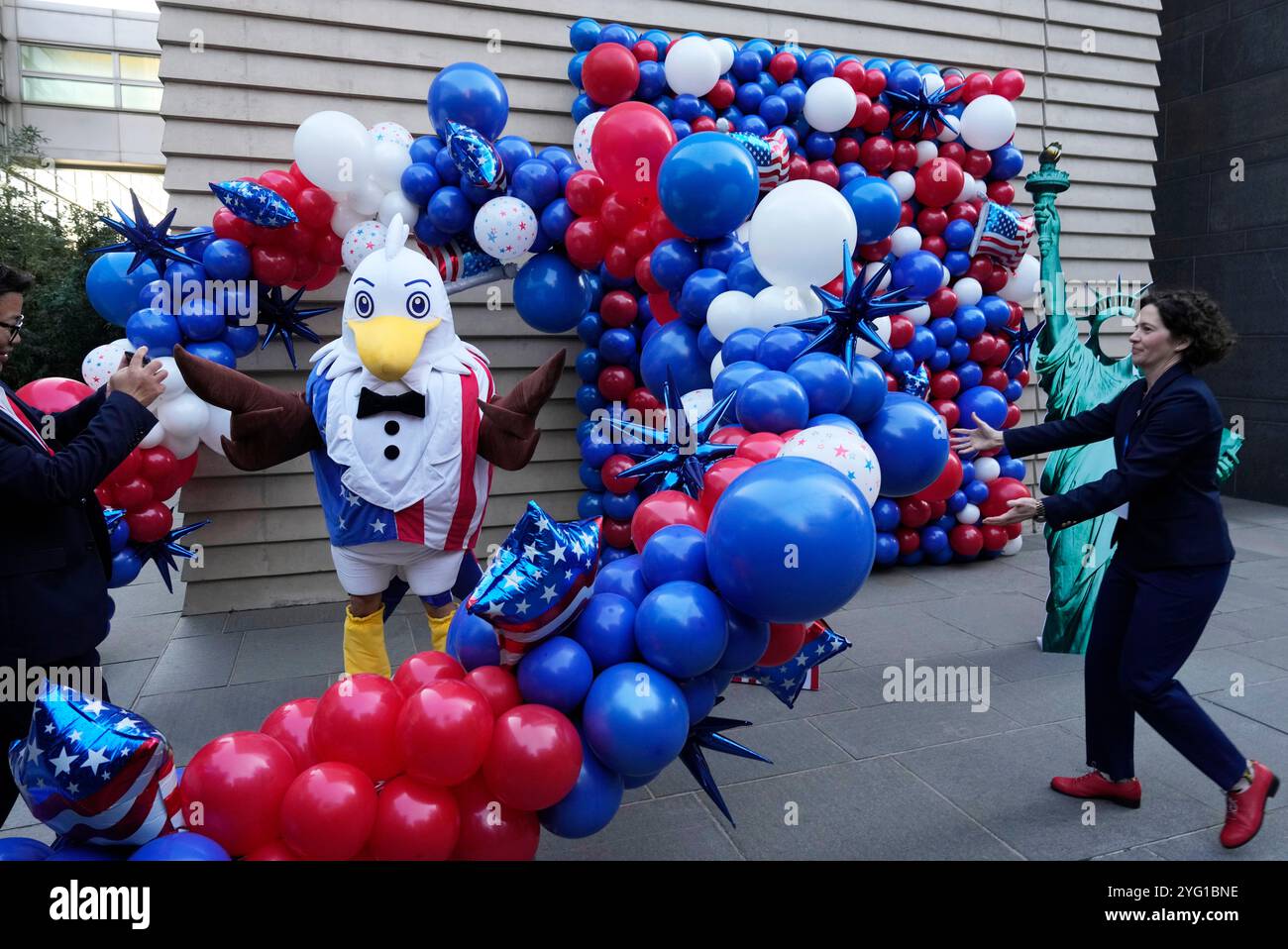 Embassy staffers react as balloon decorations fall near an eagle mascot ...