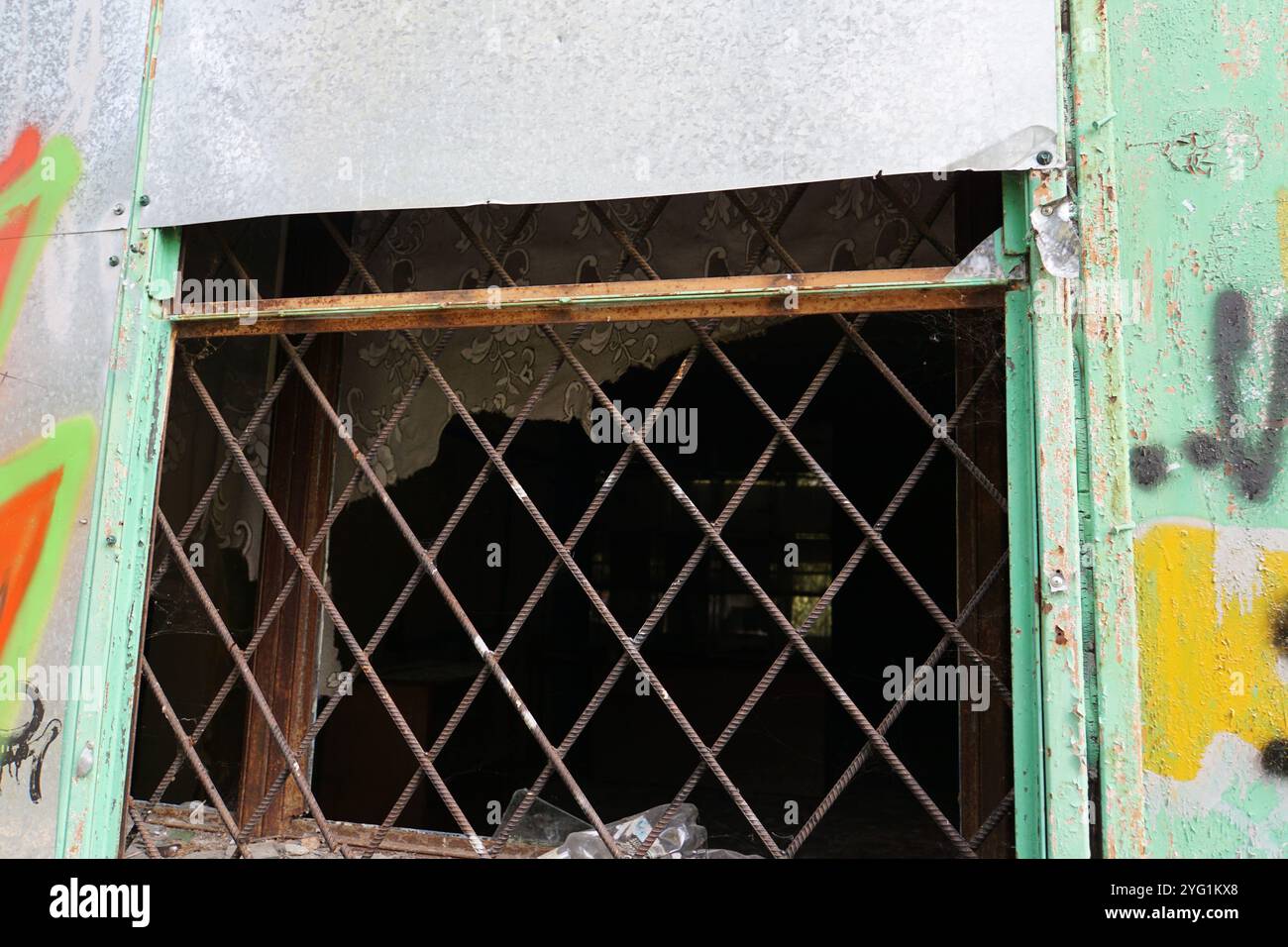 Old metal grille on the window of the empty store. Broken and abandoned ...