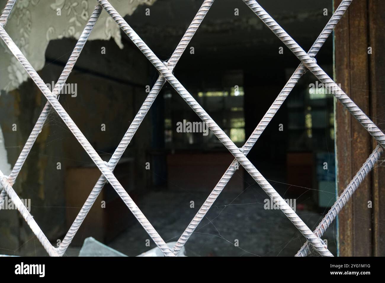 Old metal grille on the window of the empty store. Broken and abandoned ...