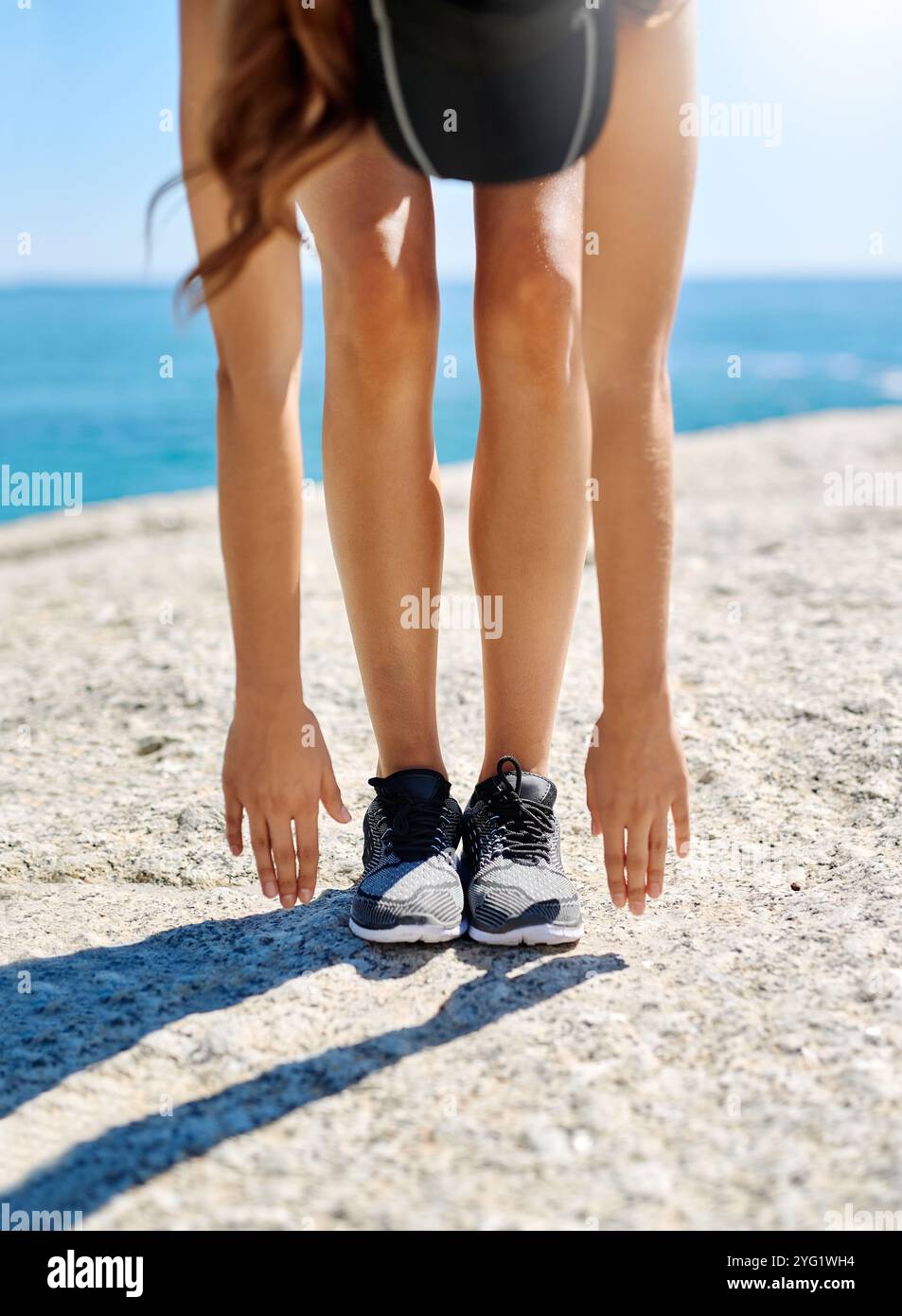 Woman, legs and stretching with hands on rock for fitness, exercise or ...