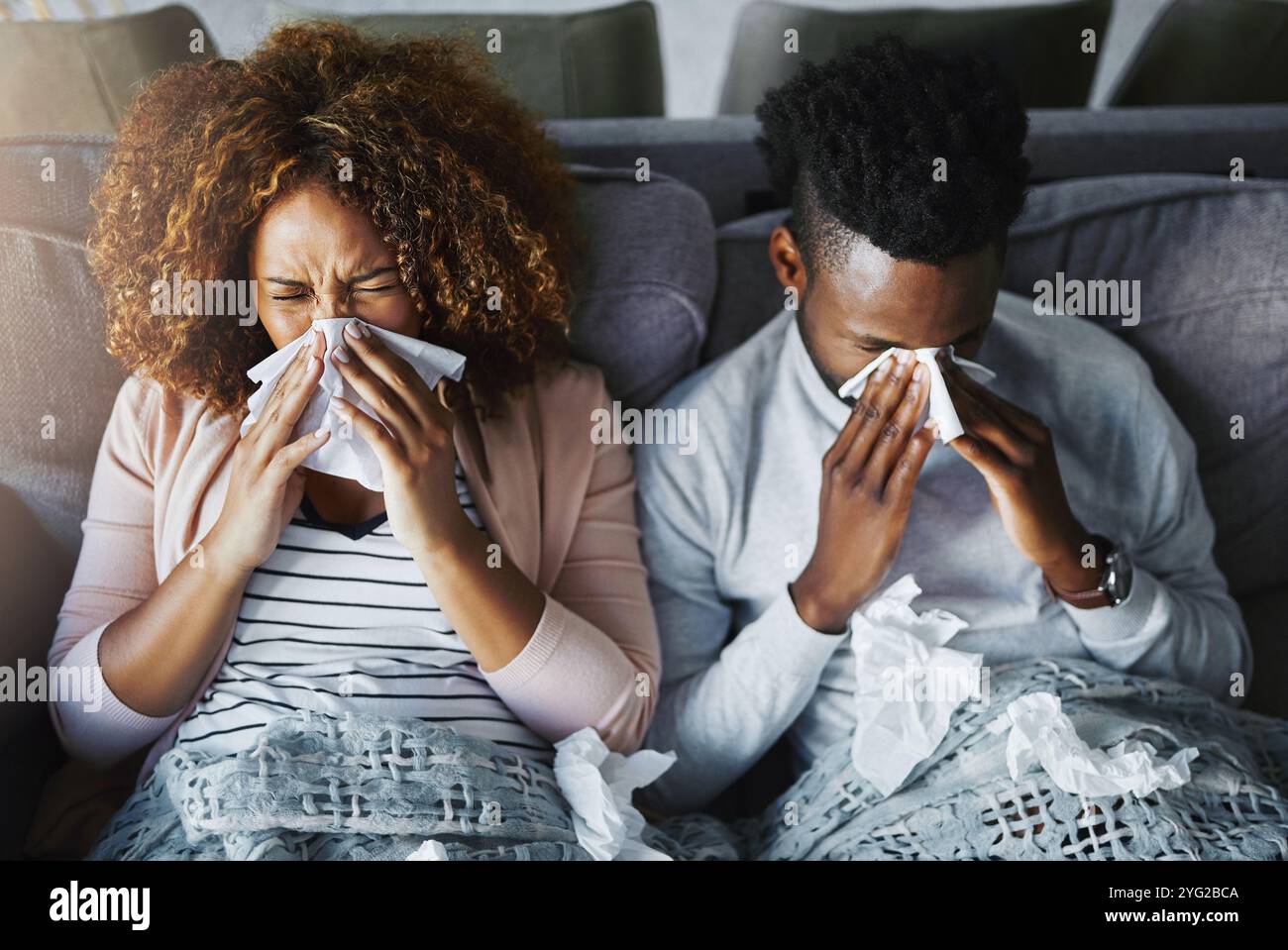 Sick couple, sneeze and blowing nose with tissue on sofa for allergy ...