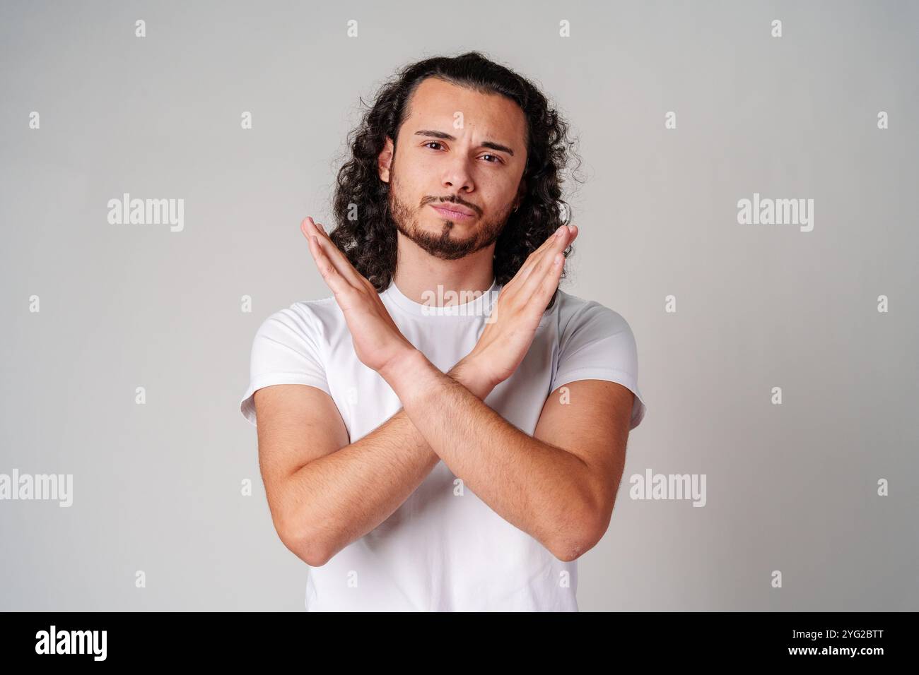 Man expressing disagreement with crossed arms gesture against a neutral ...