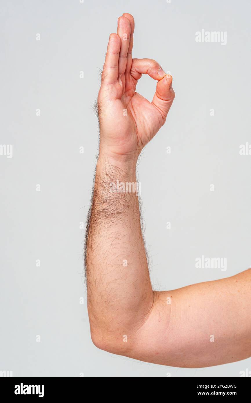 A person demonstrates the okay hand gesture with a raised arm against a ...