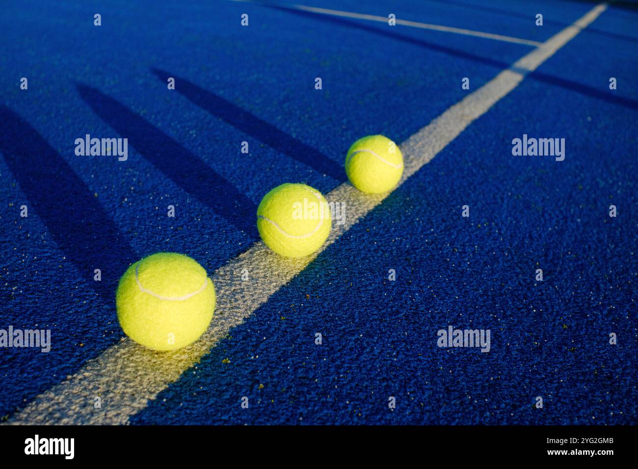 three balls in a row on a padel court line at sunset Stock Photo - Alamy