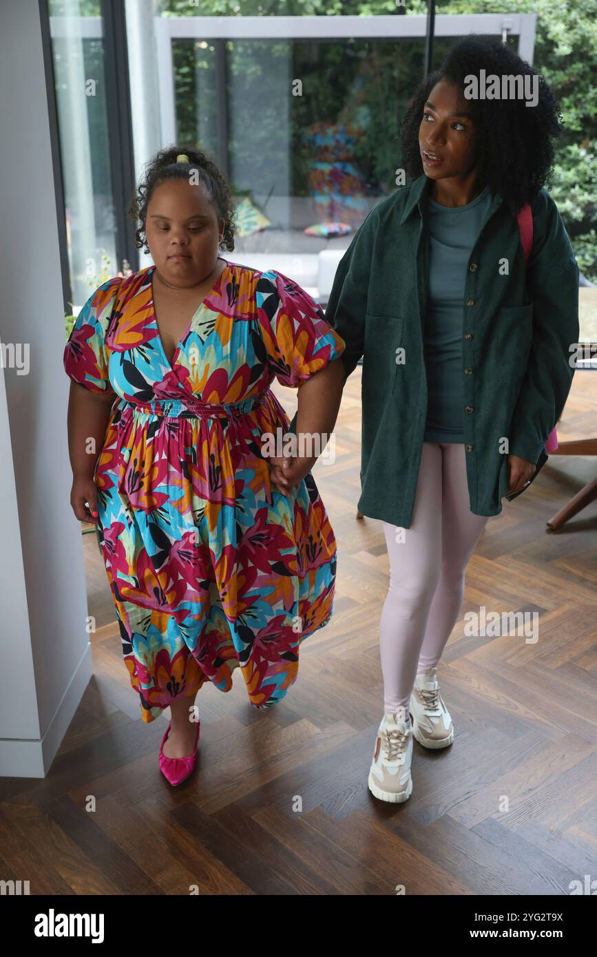 Woman supporting her friend with Down syndrome entering living room ...