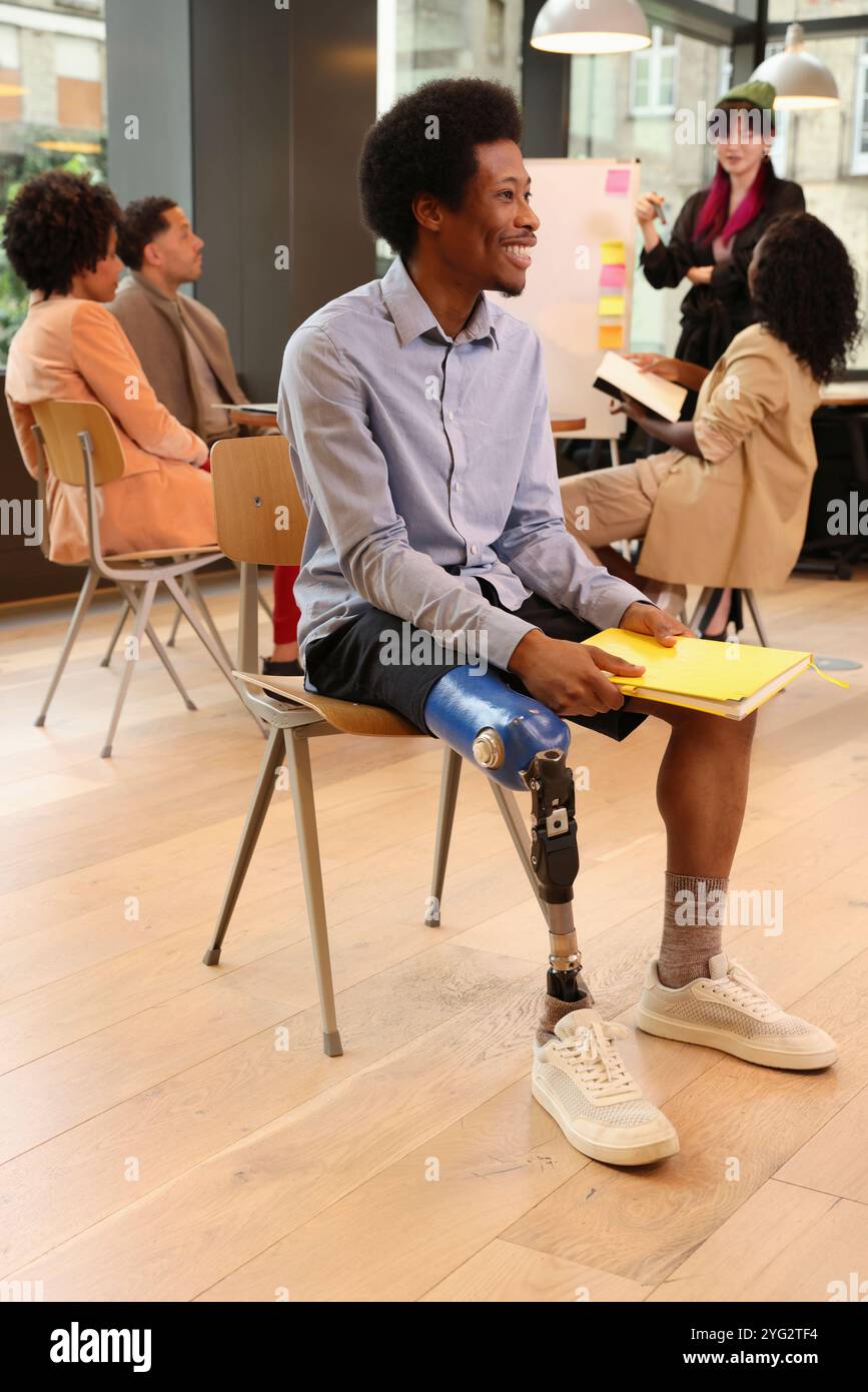 Smiling amputee businessman sitting on chair and looking away ...