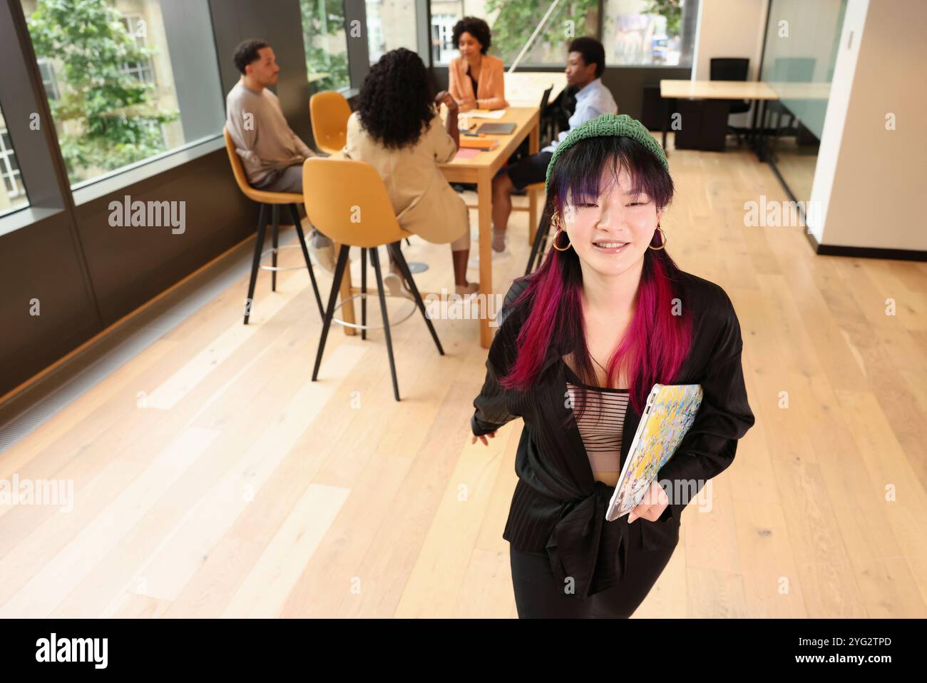 Confident businesswoman walking with laptop through office Stock Photo ...