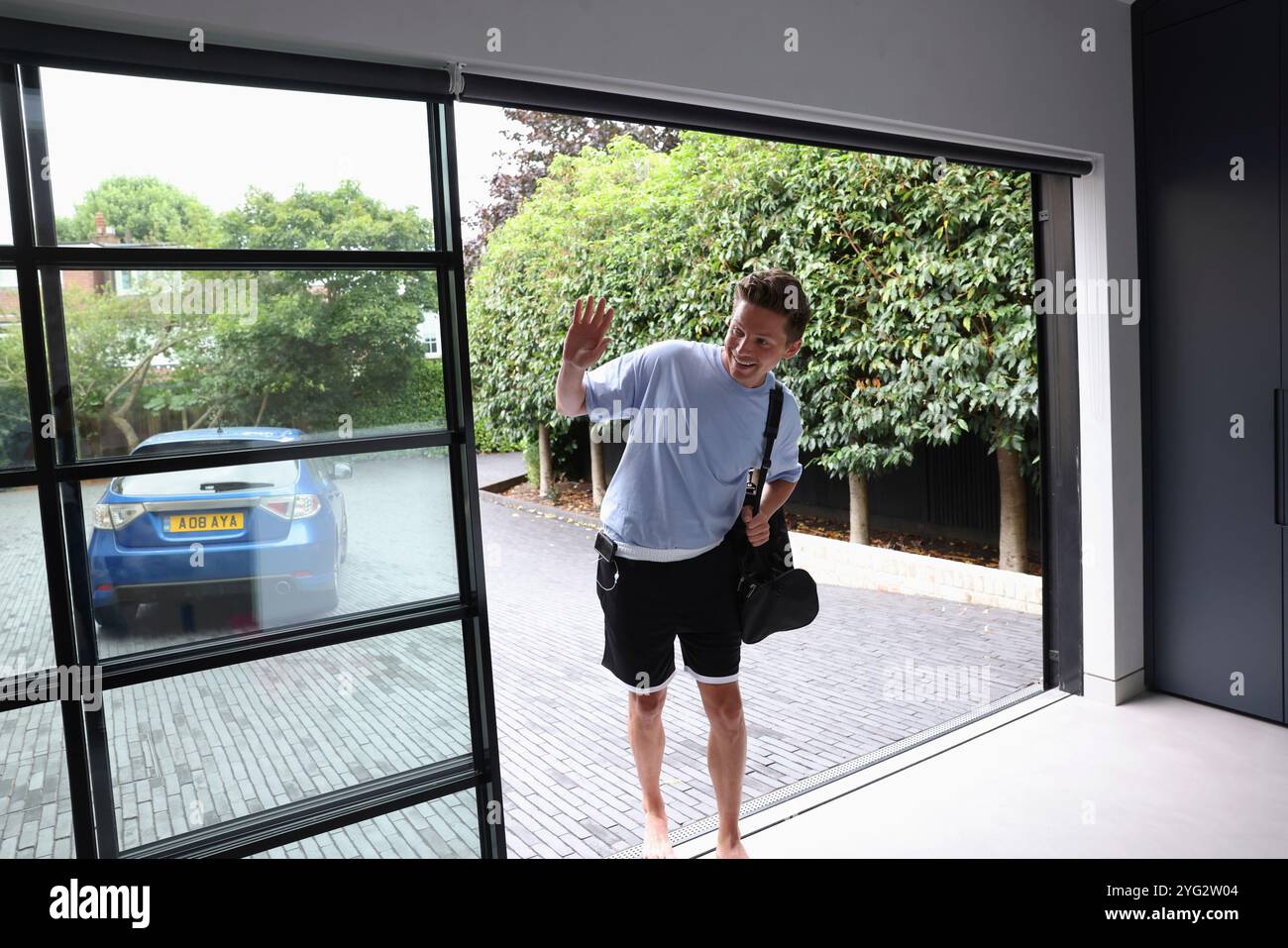 Smiling man walking inside gym with shoulder bag and waving Stock Photo ...