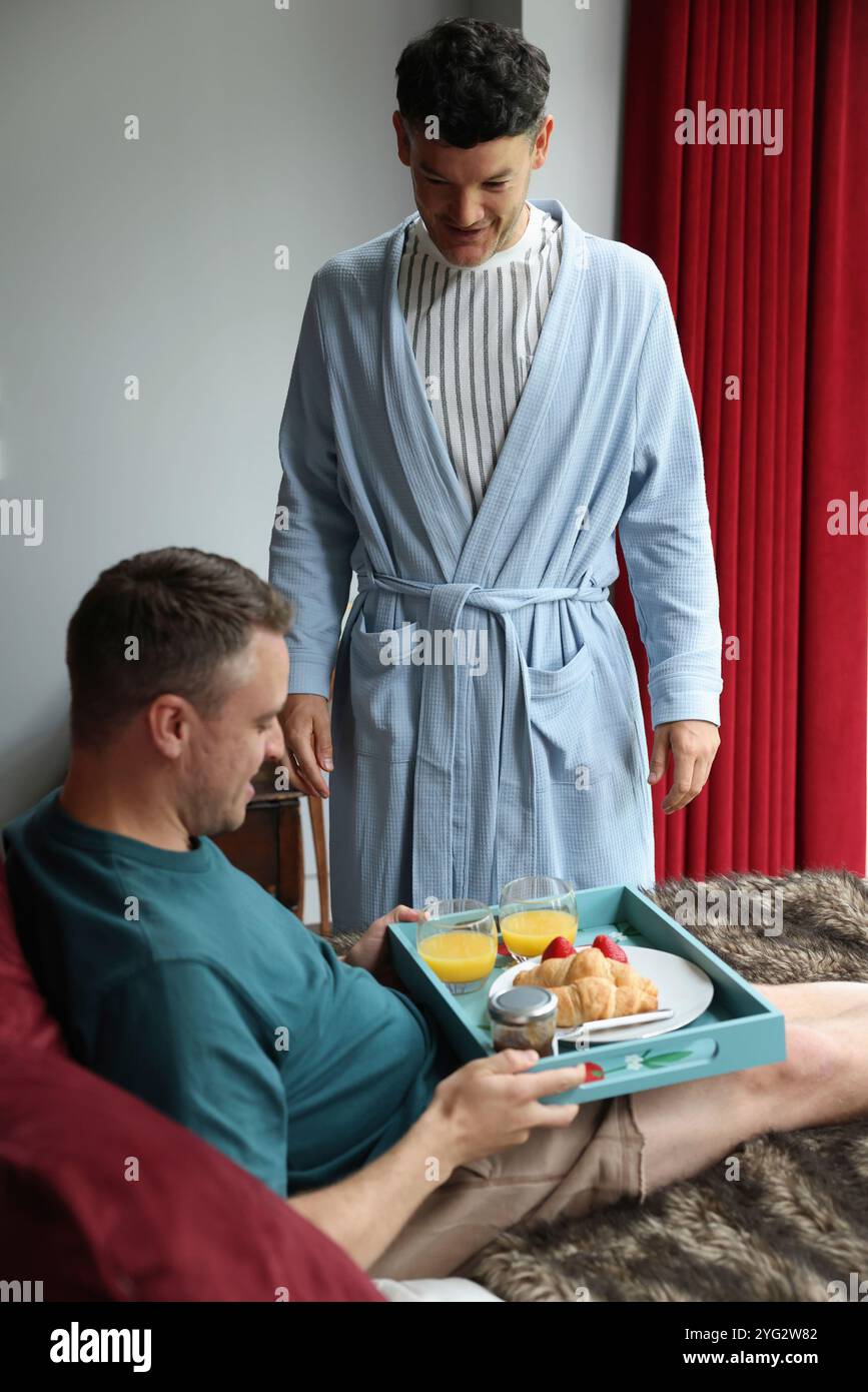 Man serving breakfast to his partner on bed Stock Photo - Alamy