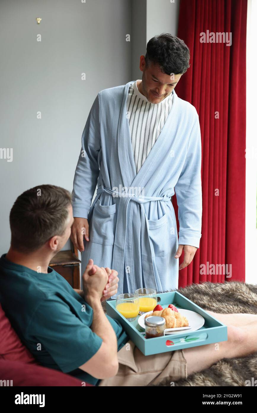 Man serving breakfast to his partner on bed Stock Photo - Alamy