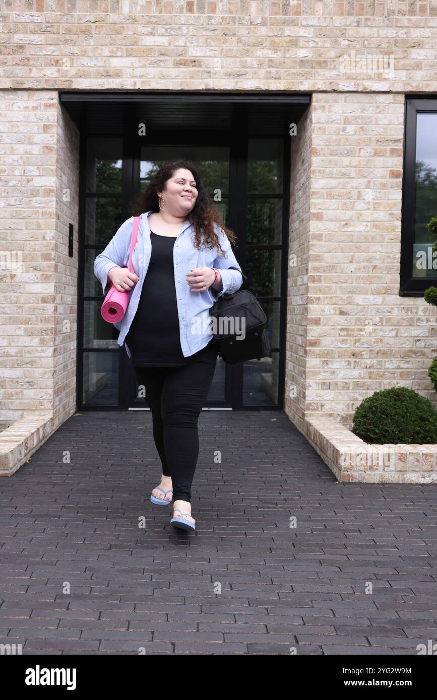 Happy woman leaving building Stock Photo - Alamy