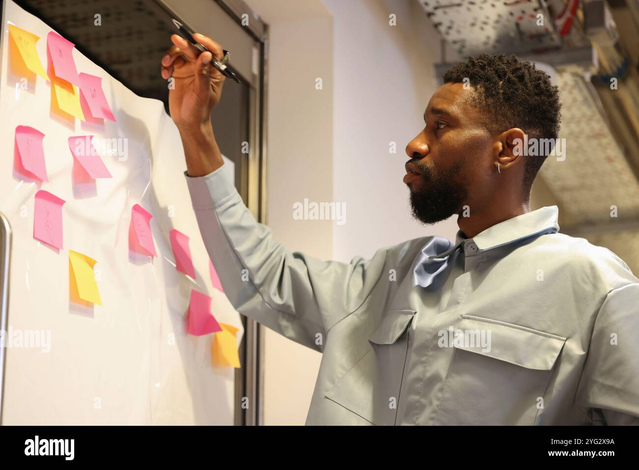 Employee making note at bulletin board Stock Photo - Alamy