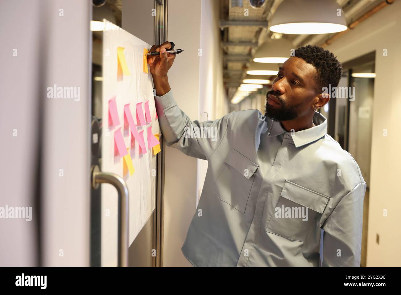 Employee making note at bulletin board Stock Photo - Alamy