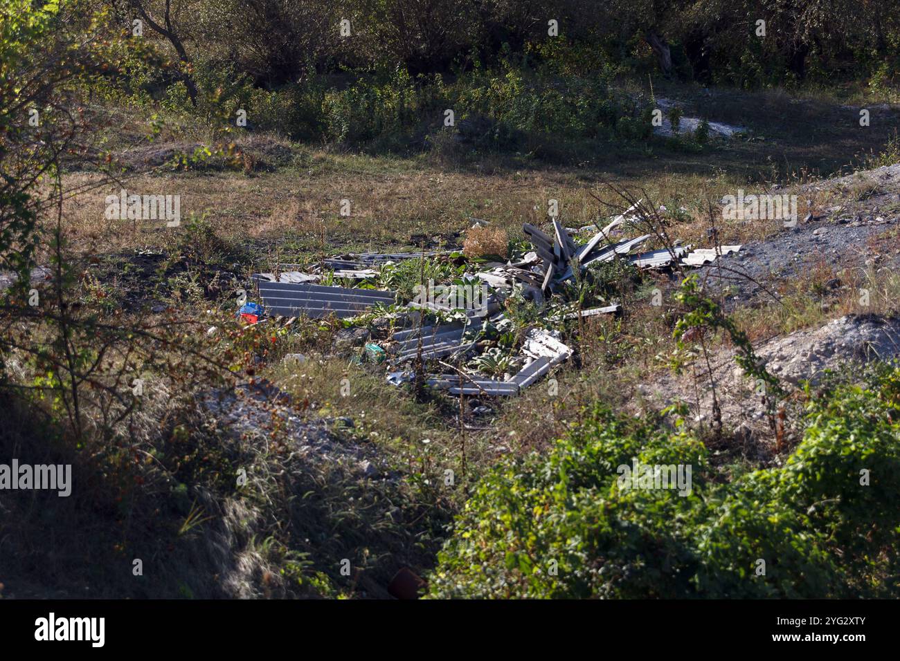 A pile of debris and debris lies scattered in a forested area ...