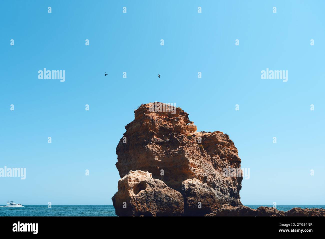 Rock formation at Praia de São Rafael, standing against a bright blue ...