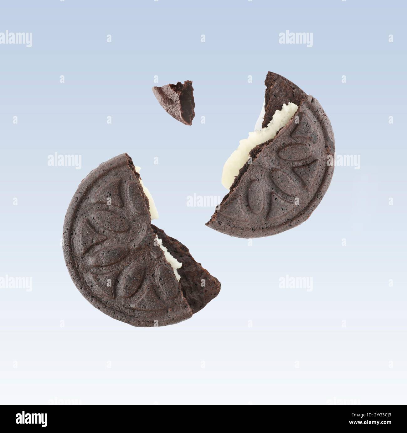 Tasty broken sandwich cookie in air on light blue gradient background ...
