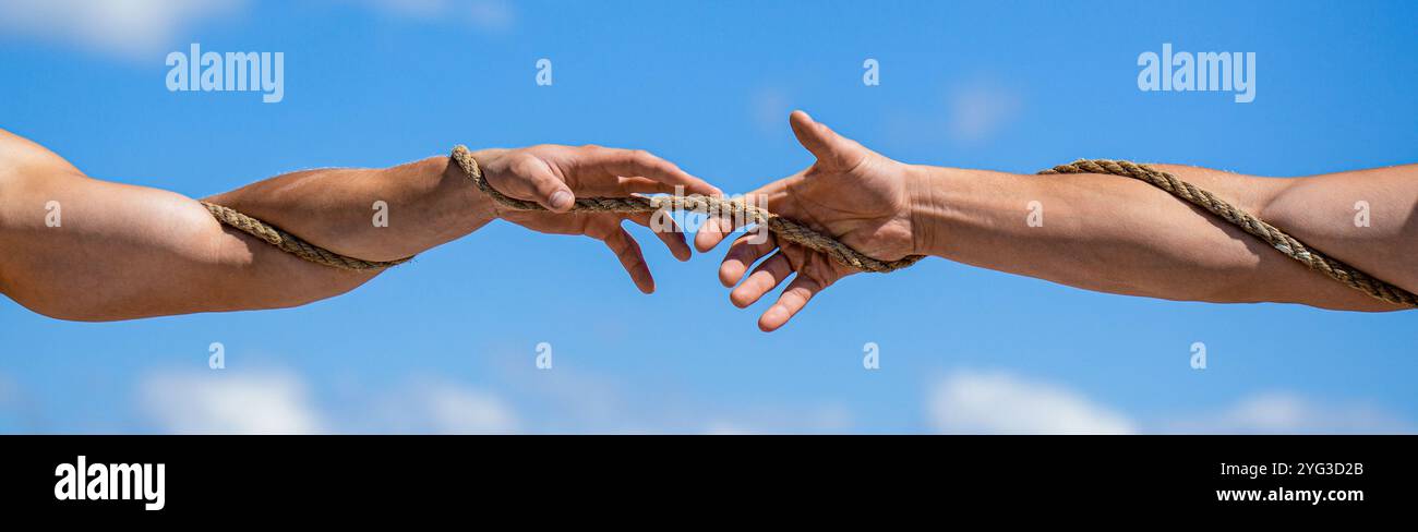 Hand holds the rope and helps the person escape.Two hands, helping hand of a friend. Rescue ...