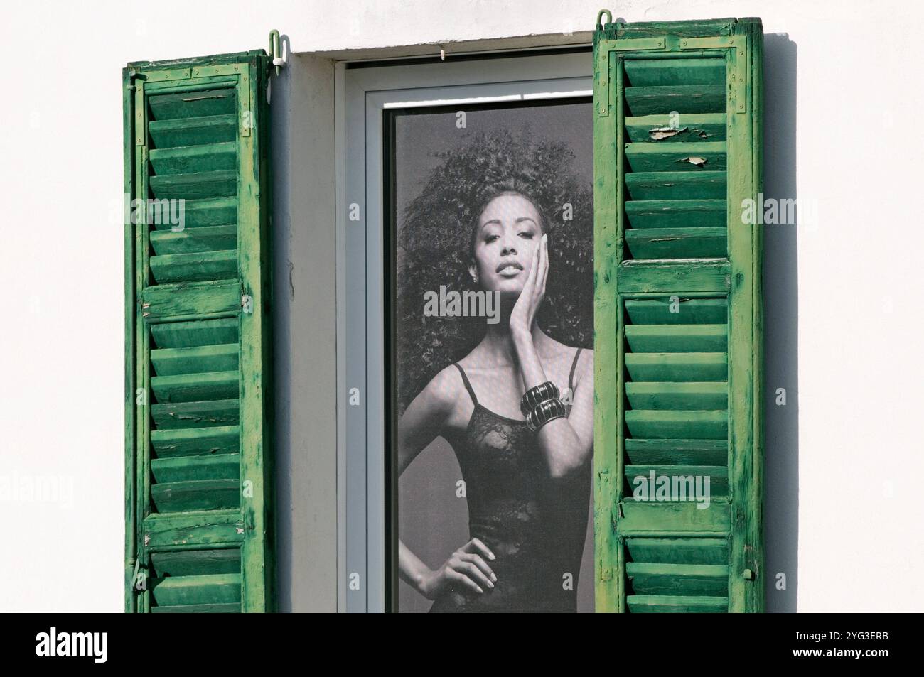 Ad poster in a store window with open shutters Stock Photo - Alamy