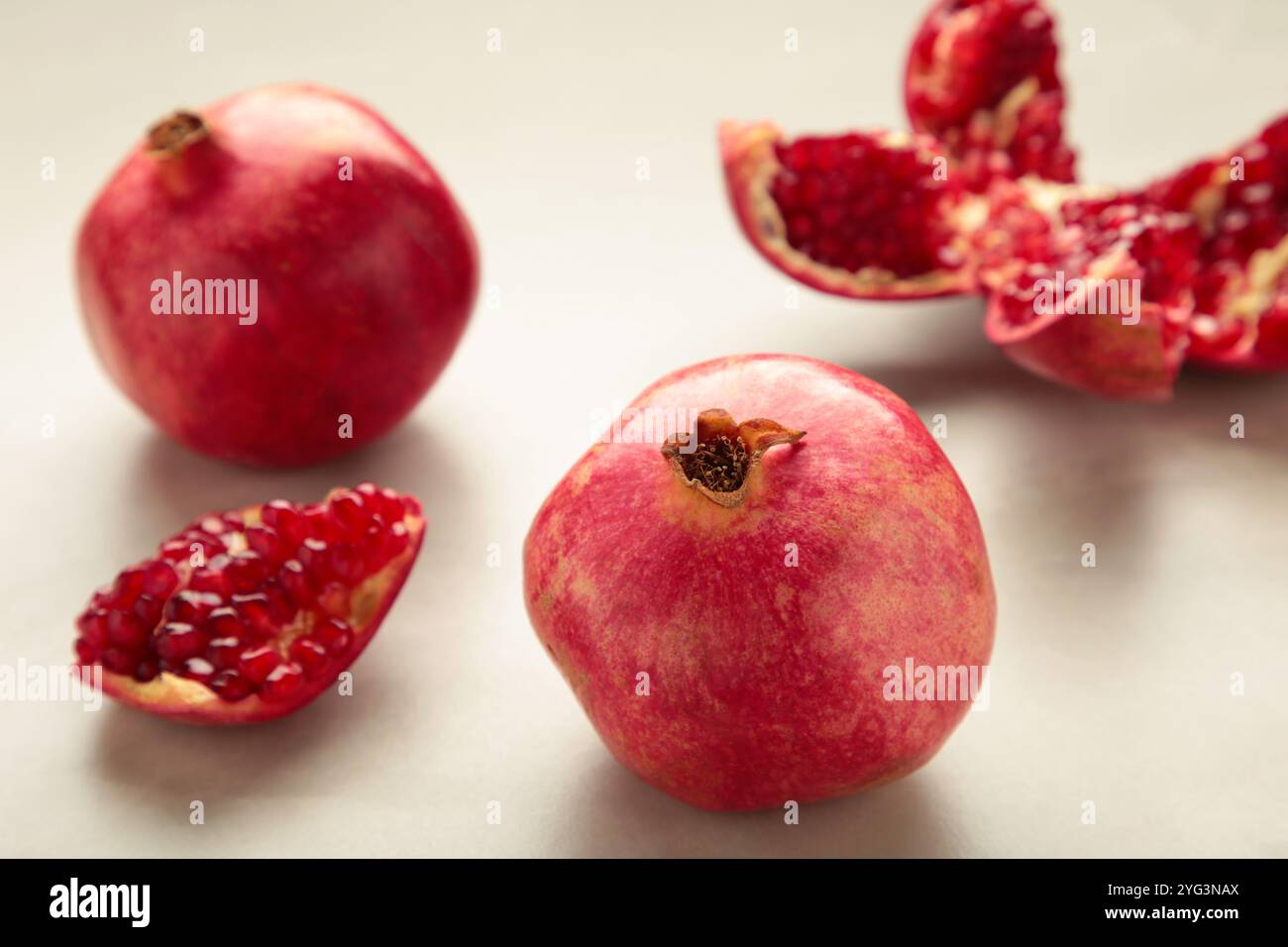 A whole pomegranate and a half-cut pomegranate with seeds on light ...