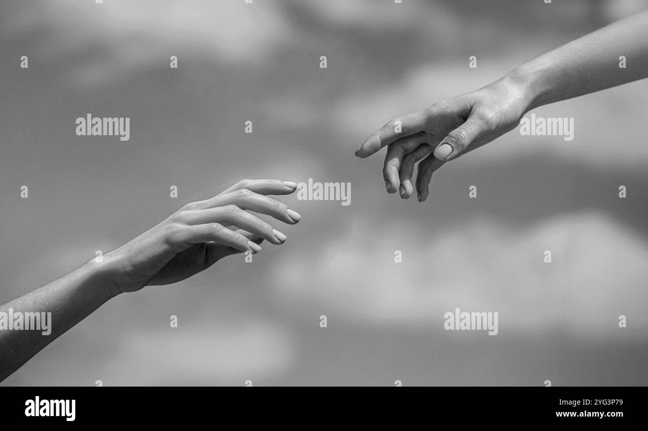 Helping hand. Two woman hands reaching towards each other on isolated sky background. Black and ...