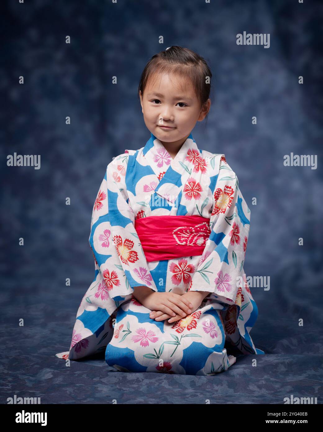 Seven-year-old girl sitting upright in yukata with a composed face ...