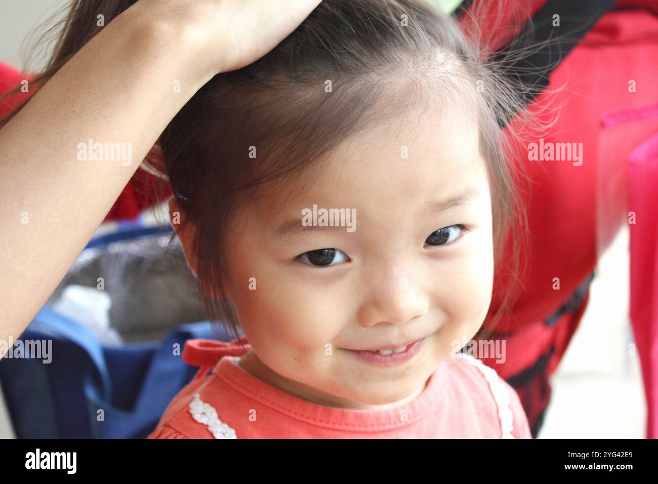 Smiling girl having her hair done by her mother Stock Photo - Alamy